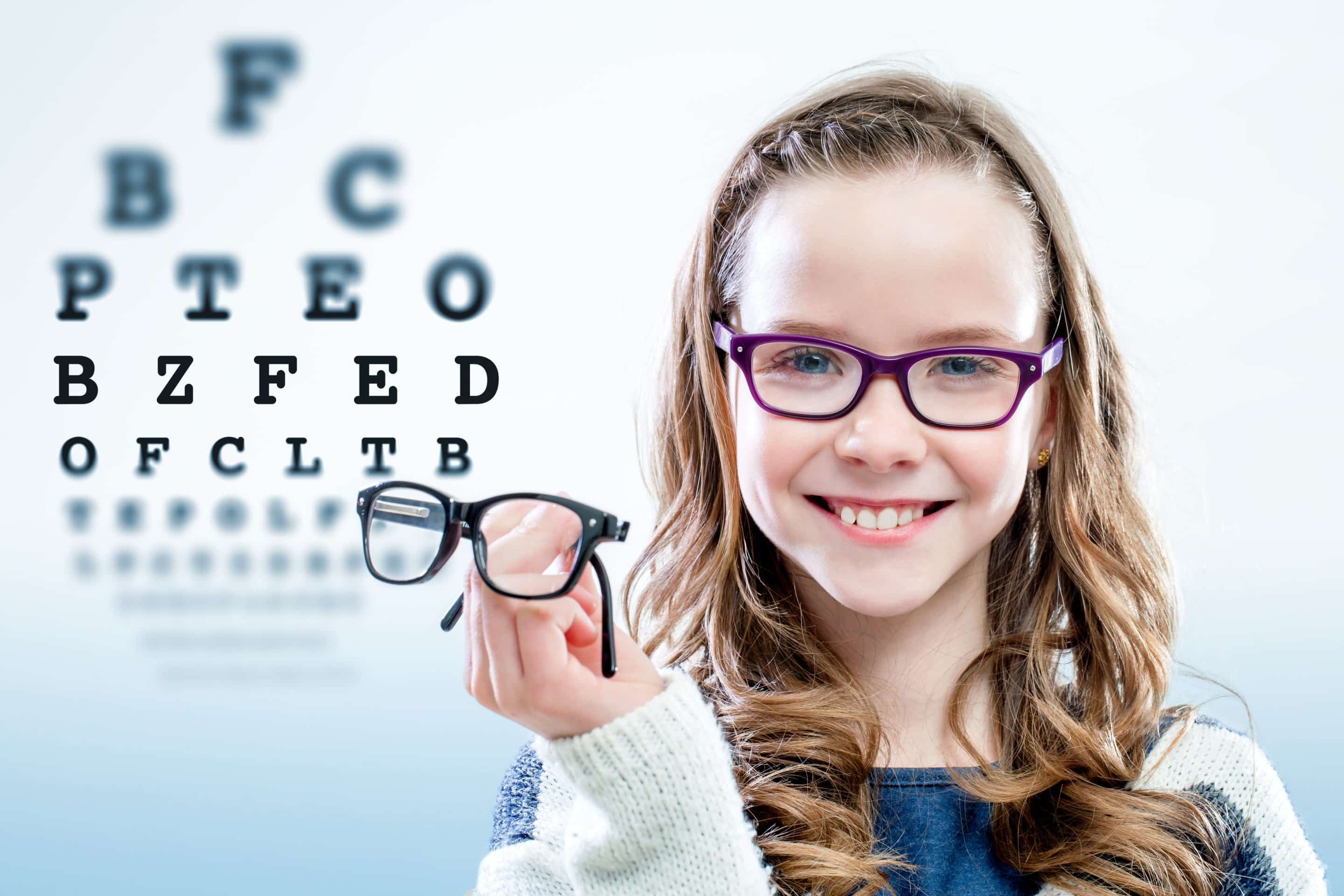 Girl Holding Glasses With Test Chart In Background Optik Huepfel Girl Holding Glasses With Test Chart In Background Optik Huepfel